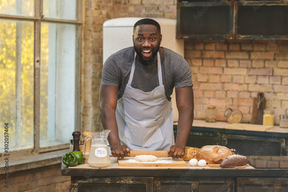 Baking process. Cheerful dark skinned African American male wears apron ...