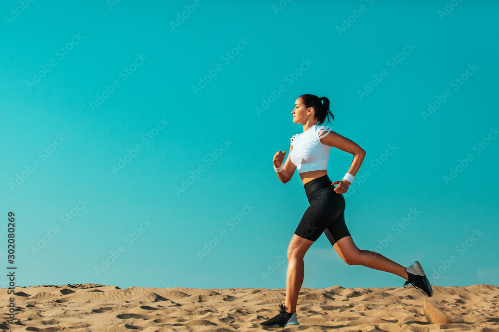 Sporty young woman and fit athlete runner running on the sky background ...