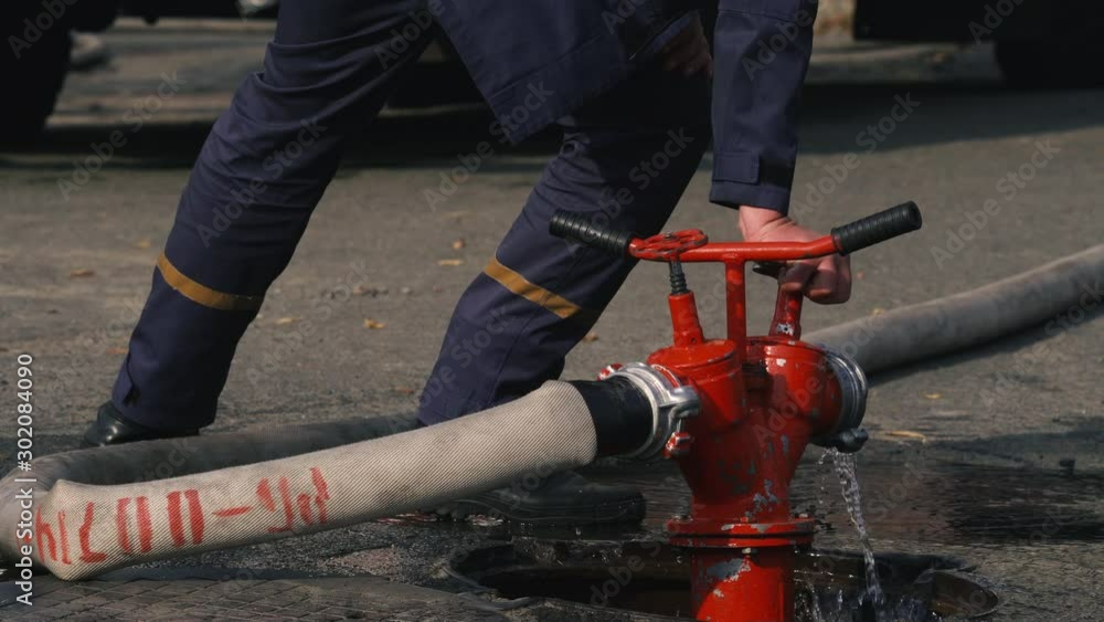 Firefighter sets up a hydrant. A stream of water from a fire hydrant ...