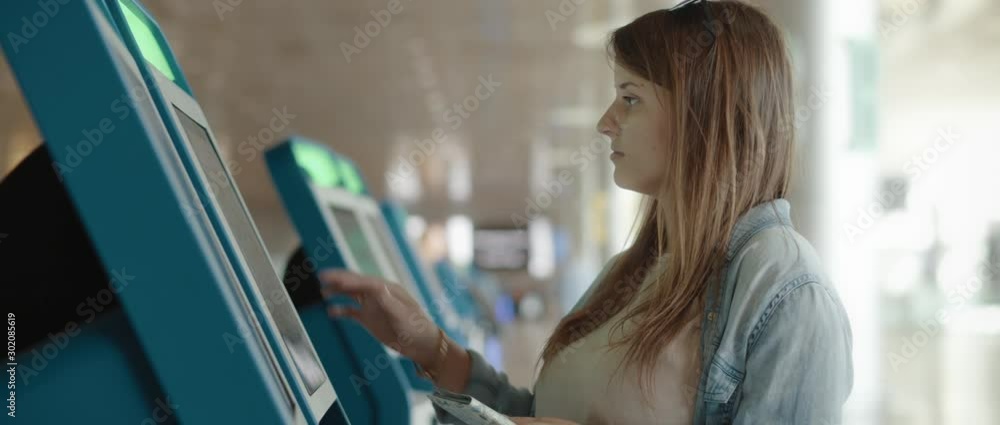 Woman using self check in desk screen at the airport terminal ...