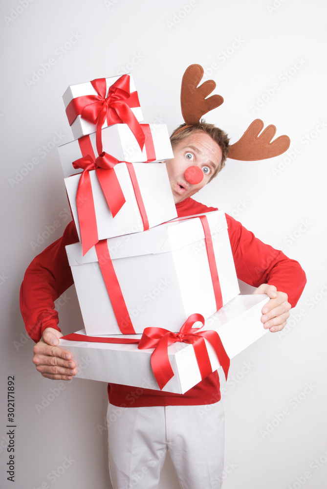 Red-nosed reindeer man standing holding a big stack of holiday presents ...