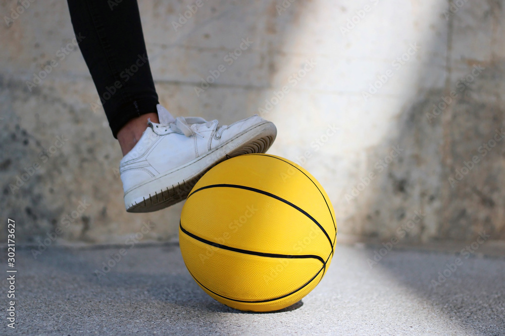 Young basketball player treading with her white shoe a yellow ...