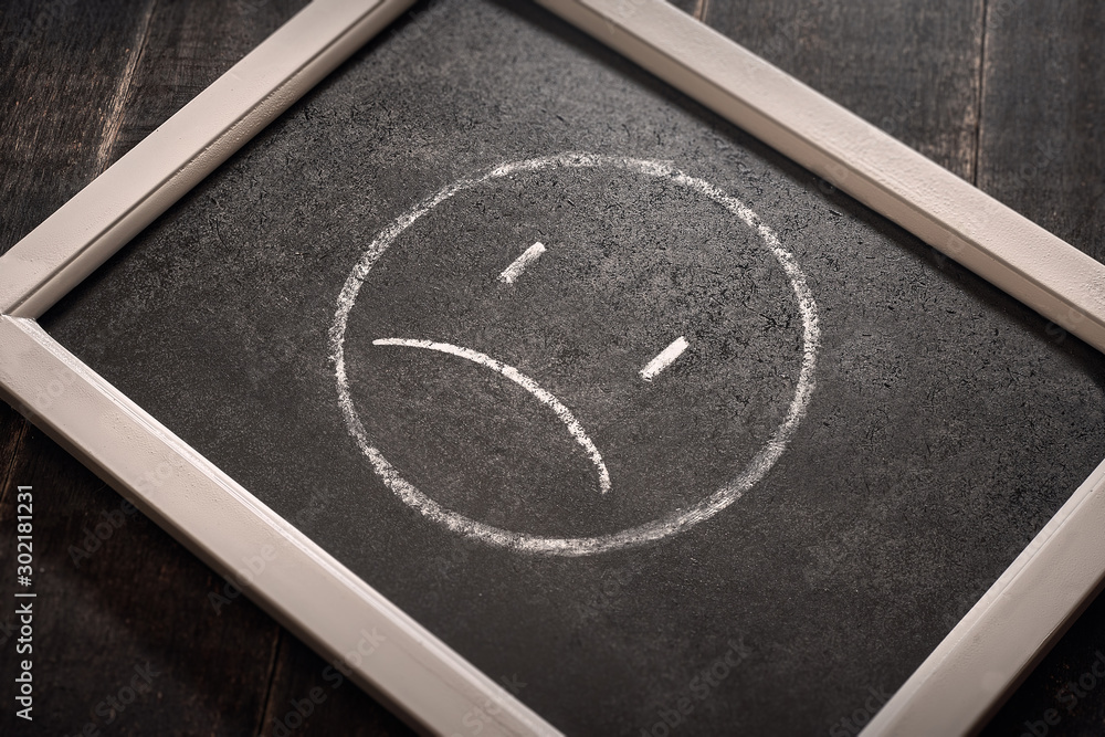 Hand drawing sad smiley face on black chalk board. Negative human ...