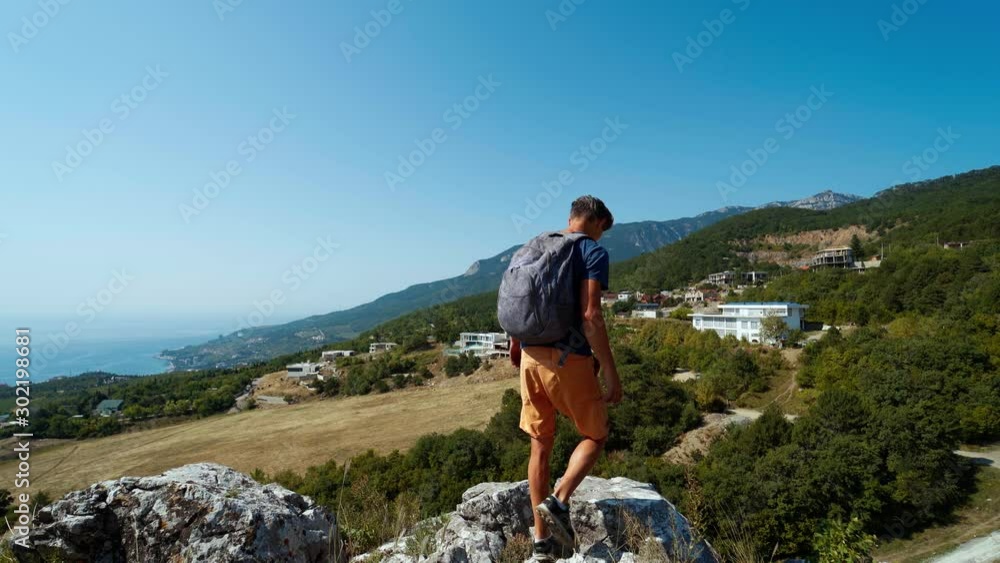 back view of happy man hiker standing on the edge of cliff on mountains ...