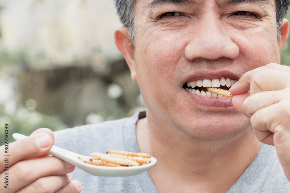 Food Insect: Man hand holding spoon eating Bamboo Worm insect or Bamboo ...