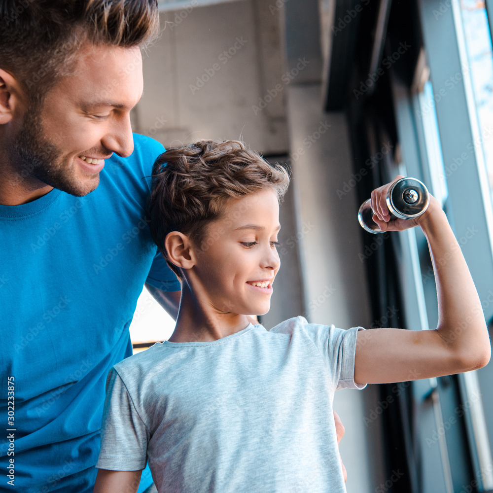 handsome father looking at cheerful son exercising with dumbbell Stock ...