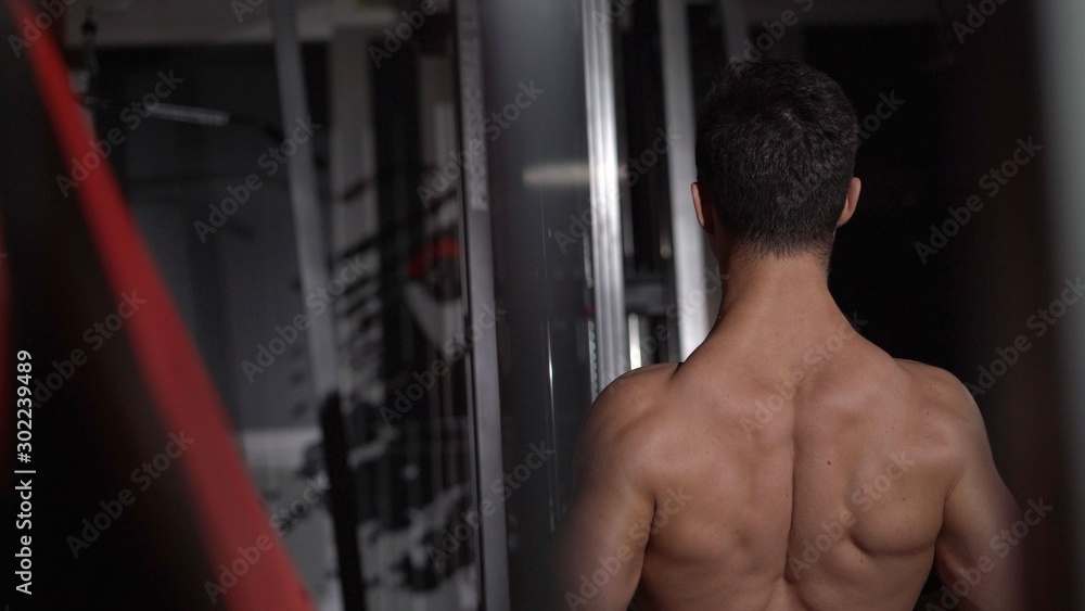 Athlete trains the back. A young athlete trains in the gym. Shows the ...