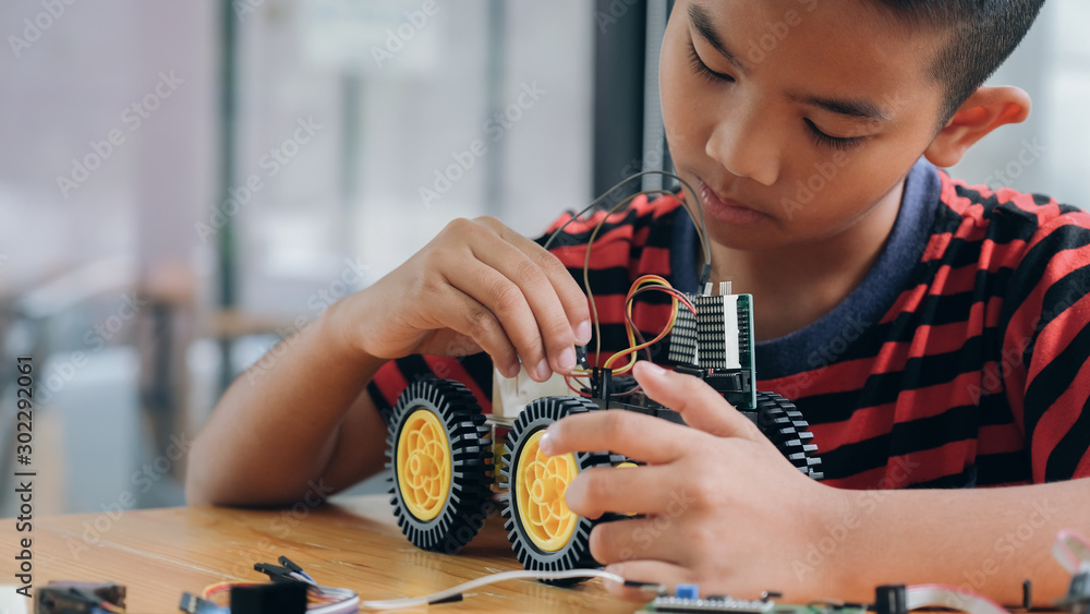 Concentrated boy creating robot at lab. Stock Photo | Adobe Stock