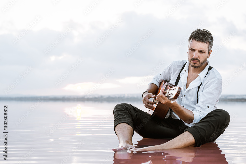 Wistful man in white shirt and suspenders carrying acoustic guitar and ...