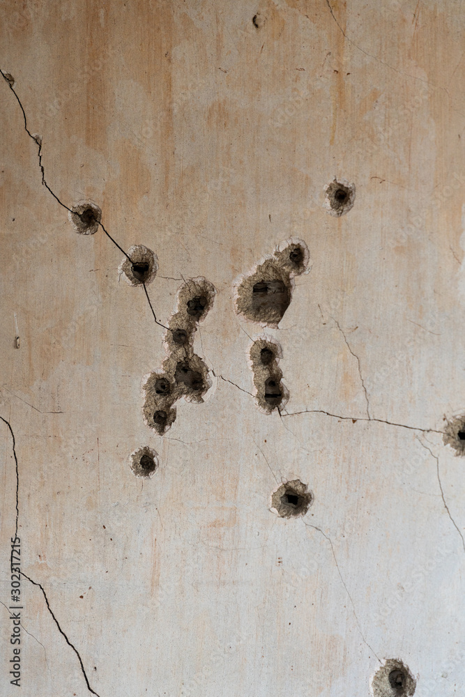 Fotka „A vertical photo of many bullet holes in a plaster wall. Dirty ...