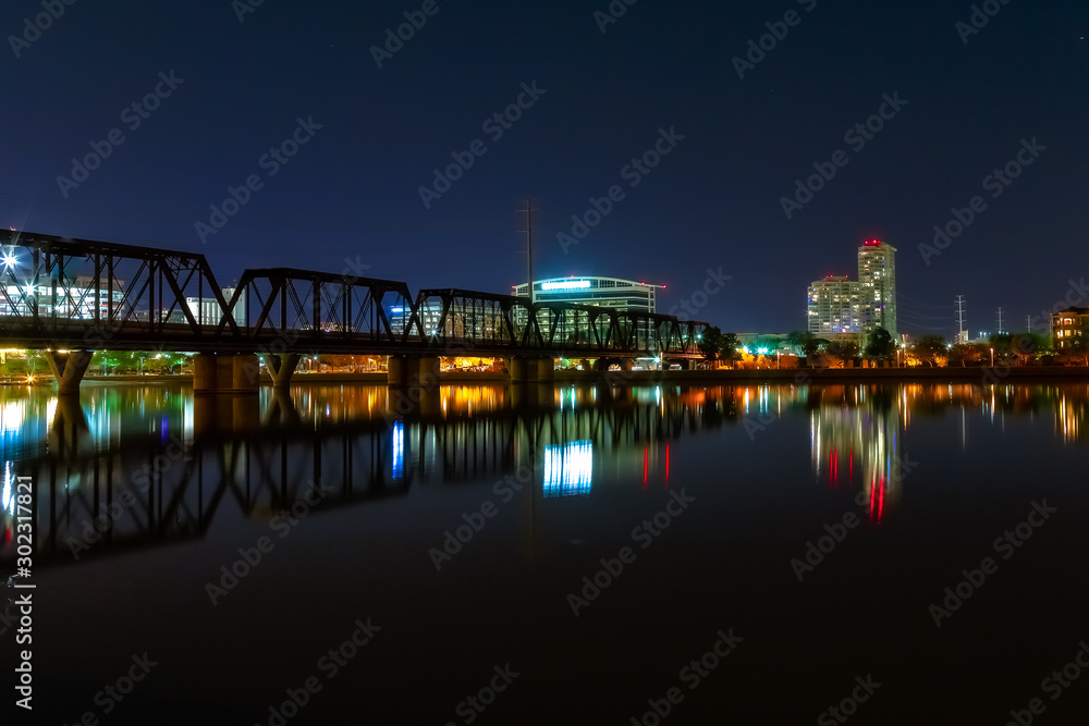Symmetrical, reflective, night time view of one part of Tempe Town lake ...
