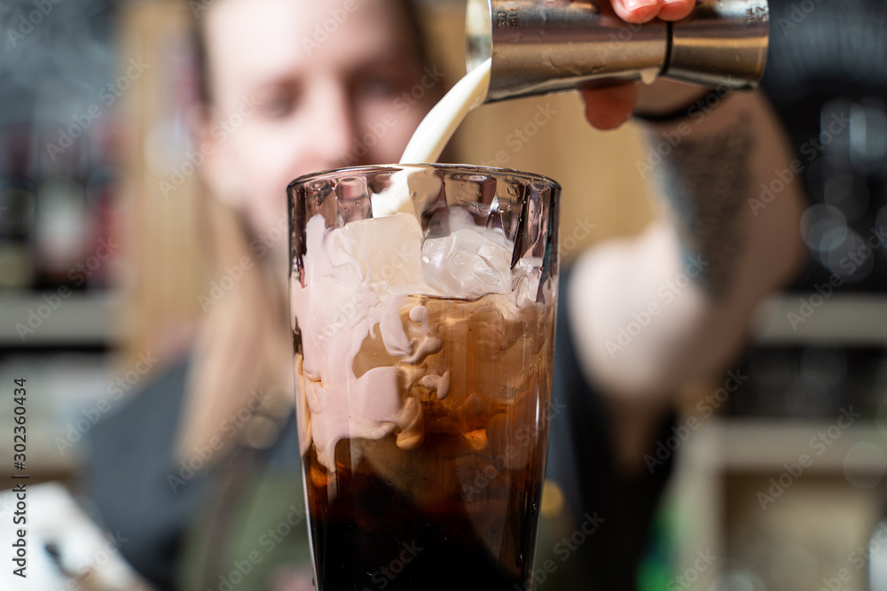 Bartender is making milky alcoholic cocktail pouring and stirring cream ...