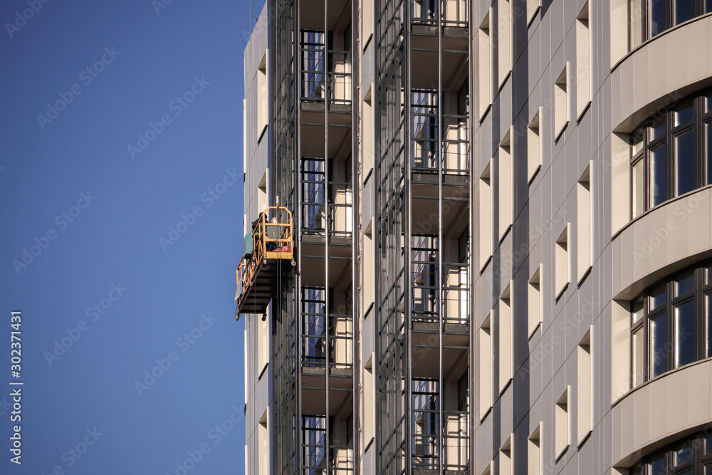 An external open building elevator rises with workers along the Stock ...