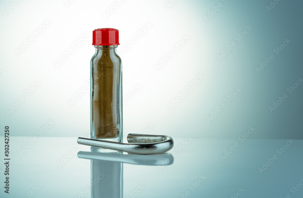 Thai herbal powders snuff in transparent glass bottle with red cap and ...