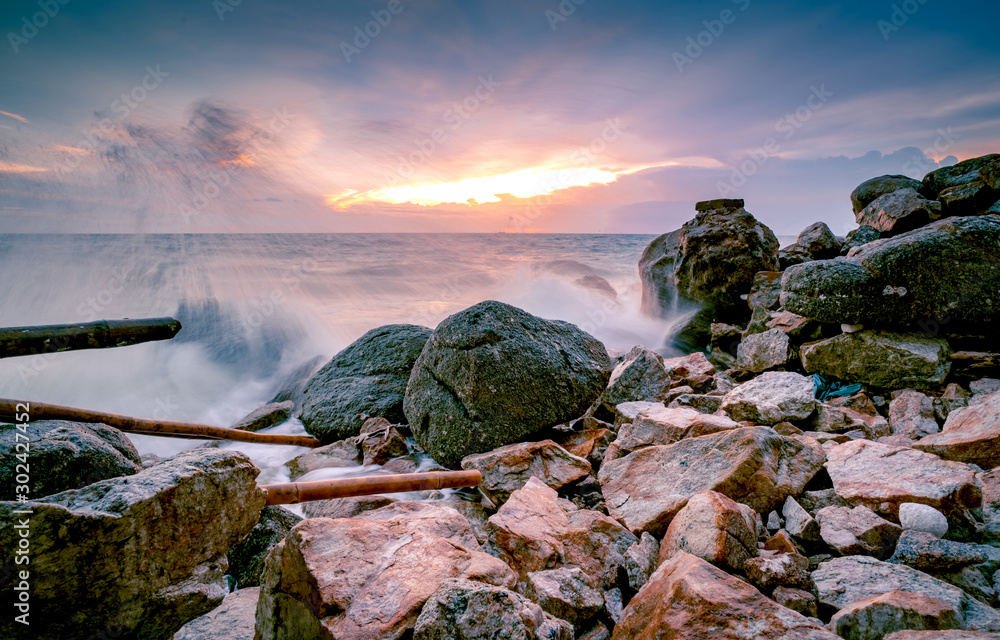 Ocean water splash on rock beach with beautiful sunset sky and clouds ...