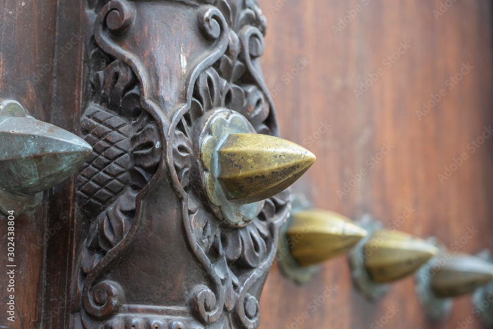 Ancient traditional wooden carved door with ornaments and bronze spike ...