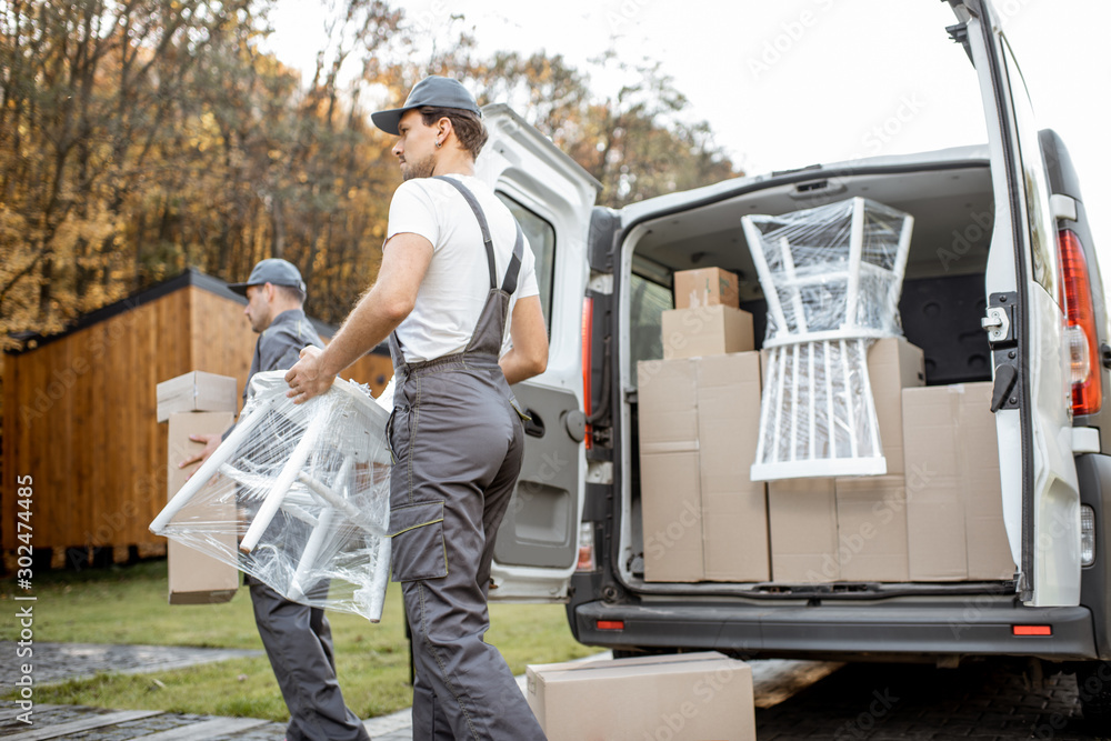 Delivery company employees unloading cargo van vehicle, delivering some ...