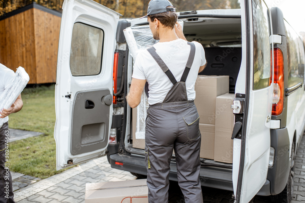 Delivery company employees unloading cargo van vehicle, delivering some ...