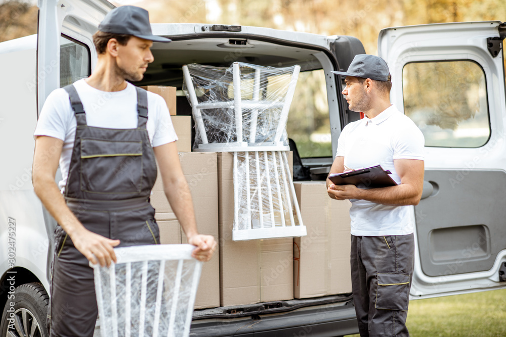 Delivery company employees unloading cargo van vehicle, delivering some ...