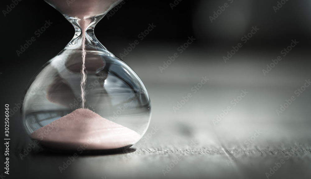 Sand running through the bulbs of an hourglass measuring the passing ...