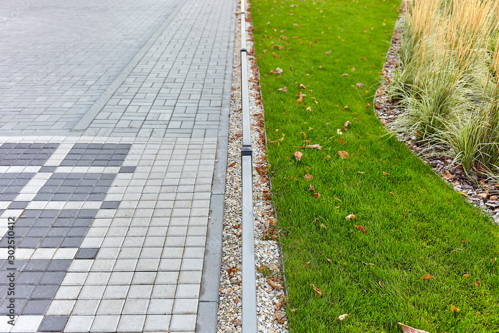 Styling paving slabs. Red paving slab next to a luxurious green lawn ...