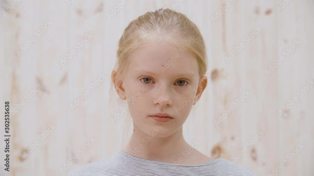 Portrait sad girl teenager looking to camera in light studio. Close up ...
