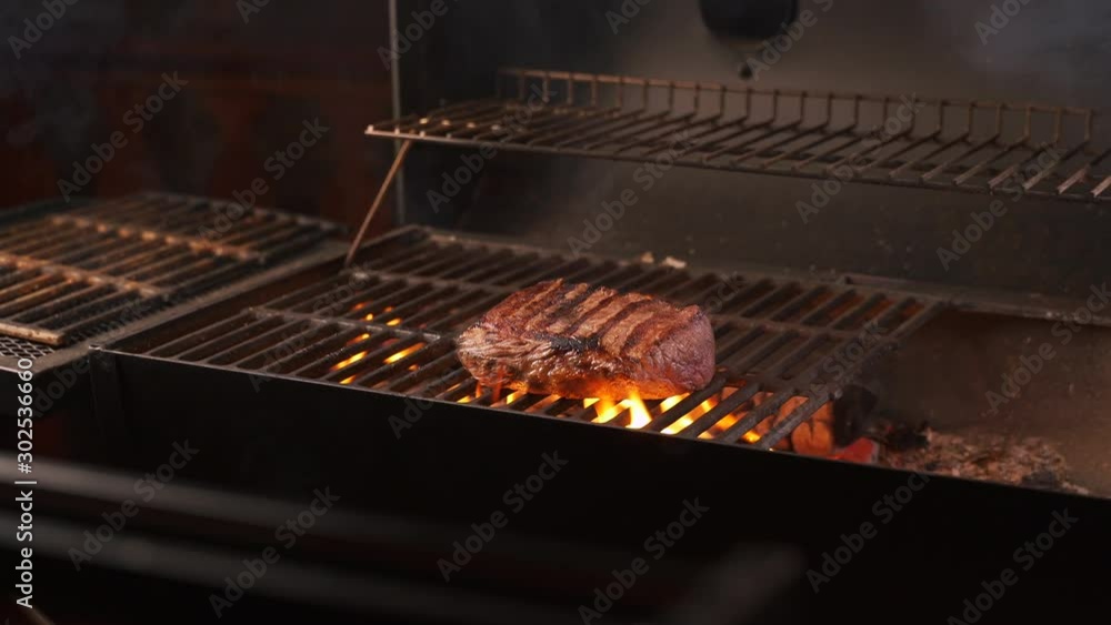 Chef opens BBQ Smoker where steak of pork beef meat cooked on fire ...