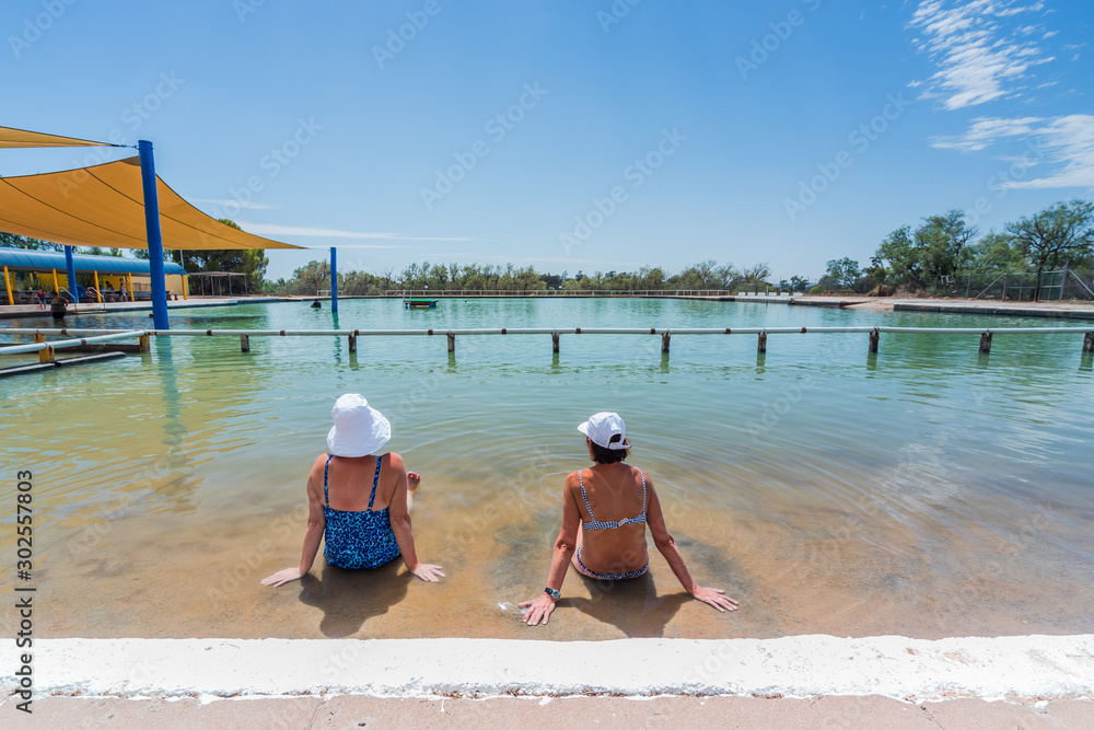 Two woman sunbathing in an Australian Outback public pool. Stock Photo | Adobe Stock