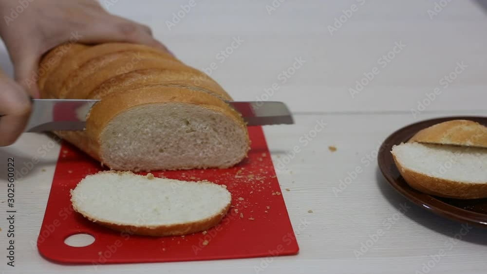 Hands cut bread on red board. Footage process of slice bread by knife ...
