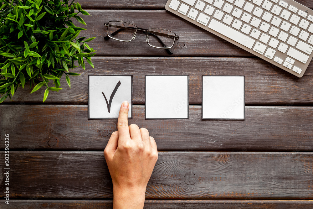 Hand put check mark in check-box on dark wooden office background top ...