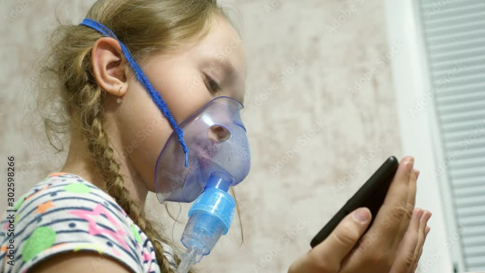 child with a tablet is sick and breathes through an inhaler. close-up ...