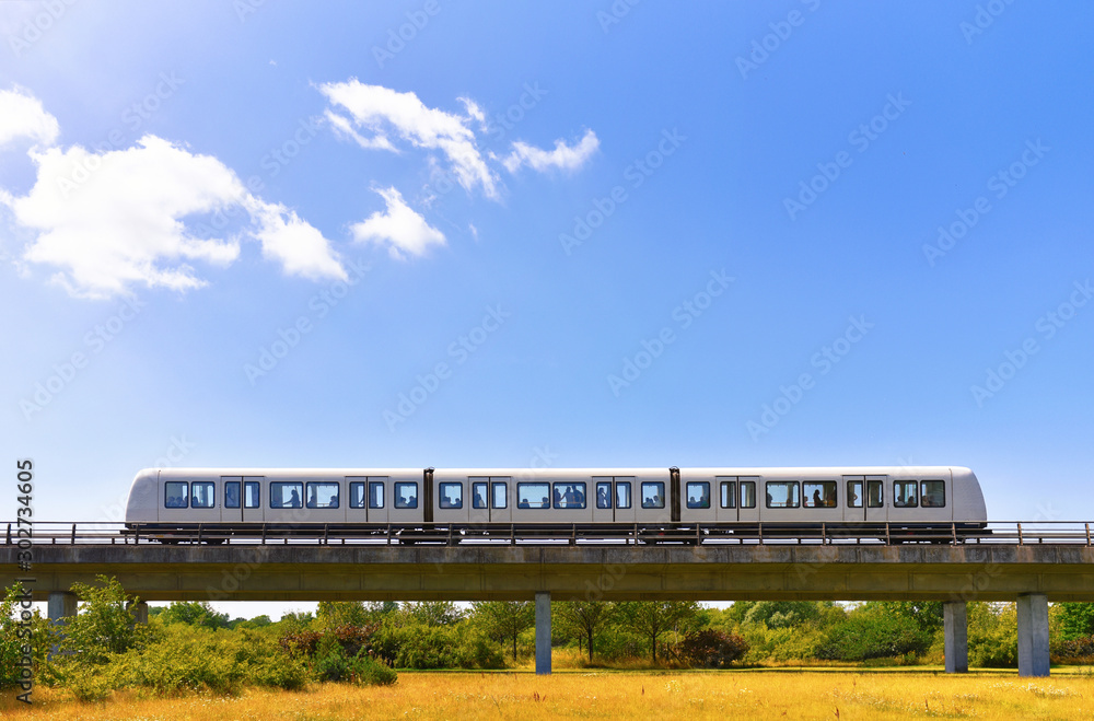 Driverless metro train is moving by overground railroad in countryside ...