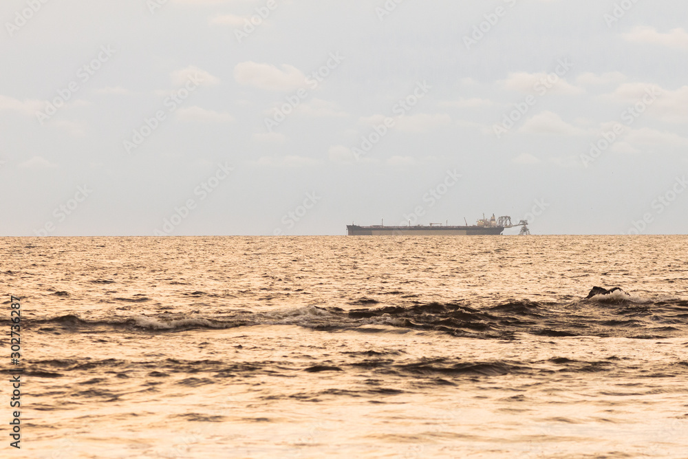 Sunset side view, from the shore, of FPSO, Floating Production Storage ...