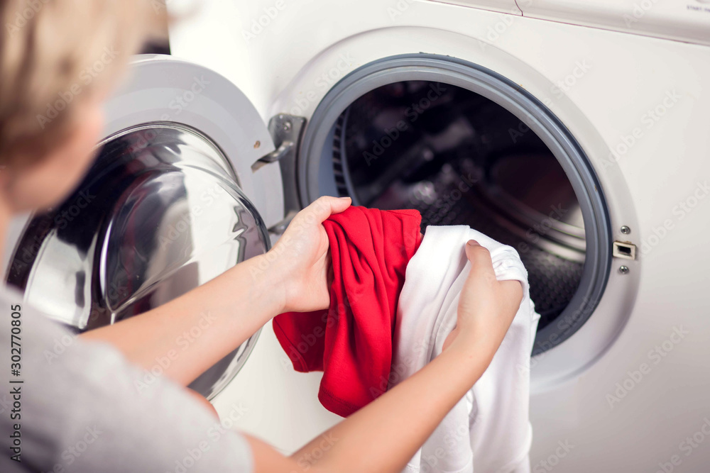 Loading white and color clothes in washing machine. Washing clothes in ...
