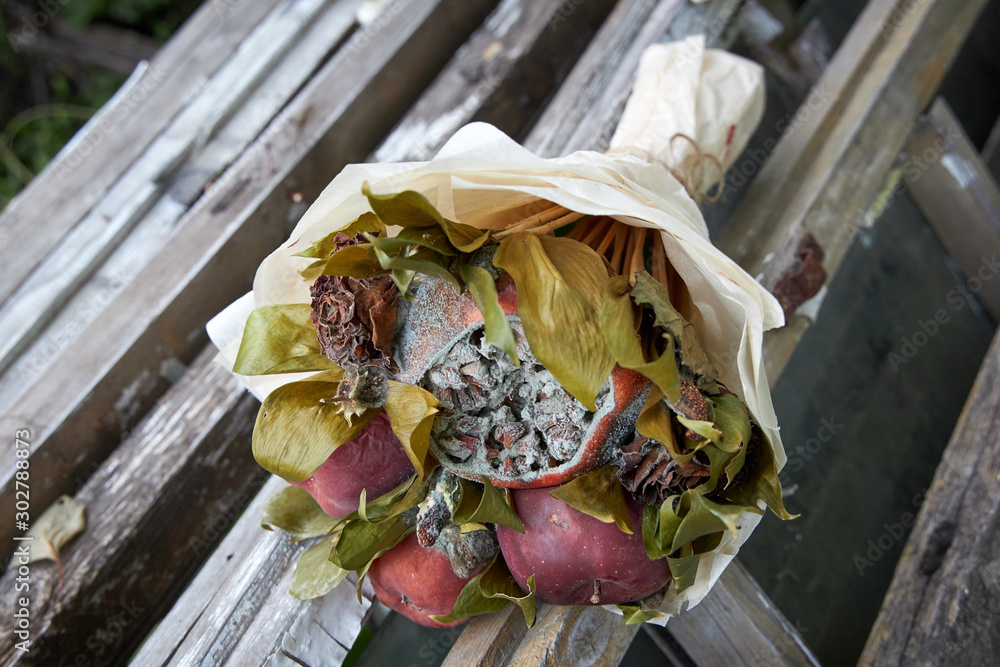 Bouquet of rotten fruit and wilted flowers lies on the remains of a ...
