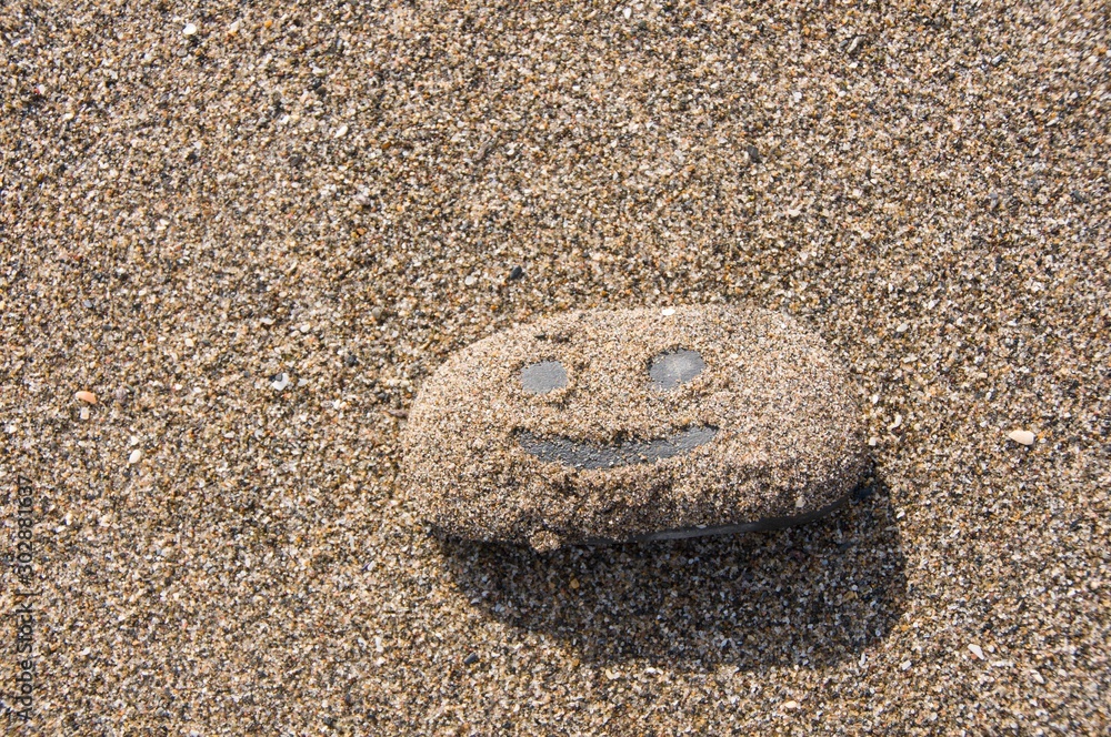 Smiling face pictured on sandy pebble Stock Photo | Adobe Stock