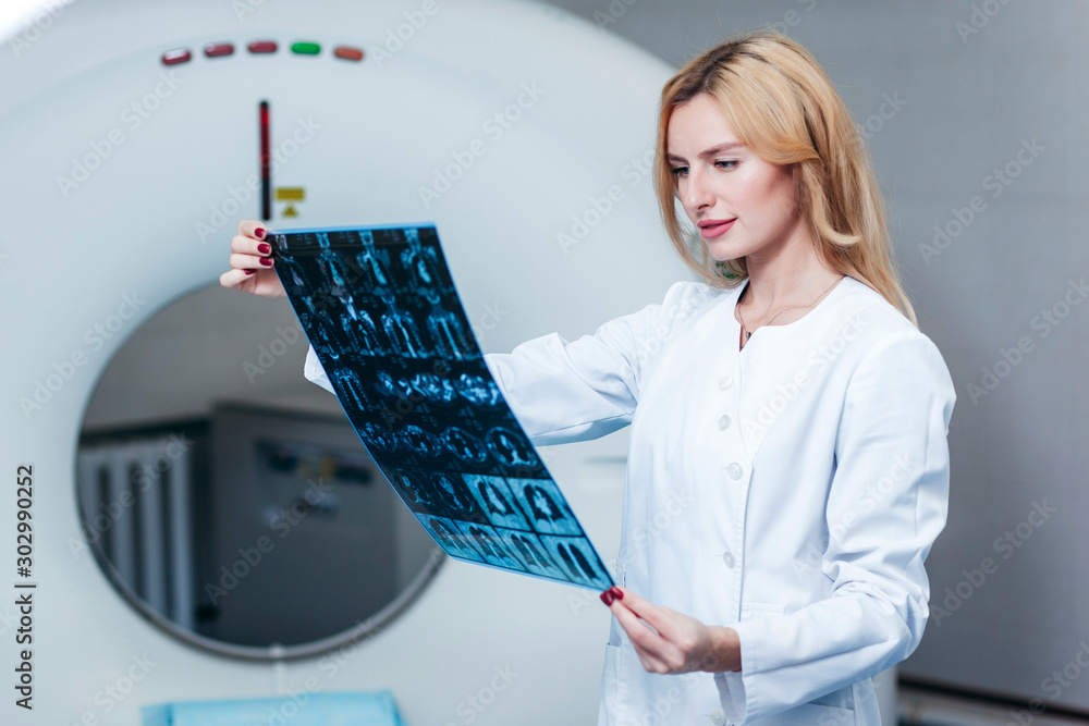 Poster Young doctor look computer tomogram picture on spiral CT scan ...