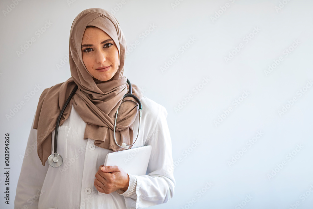 A female Muslim medical doctor stands proudly and smiles for the camera ...