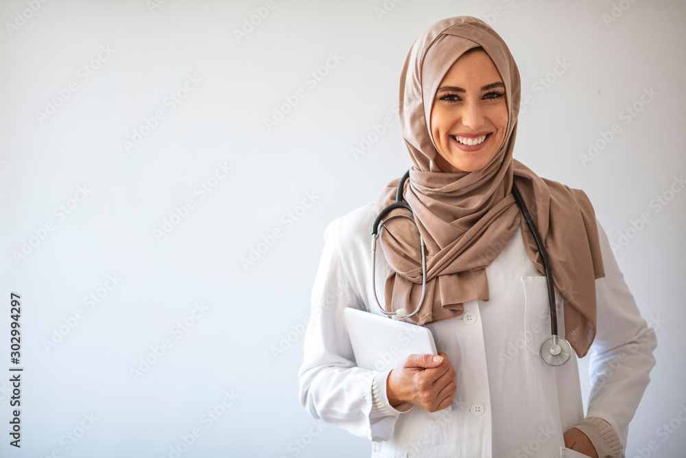 A female Muslim medical doctor stands proudly and smiles for the camera ...
