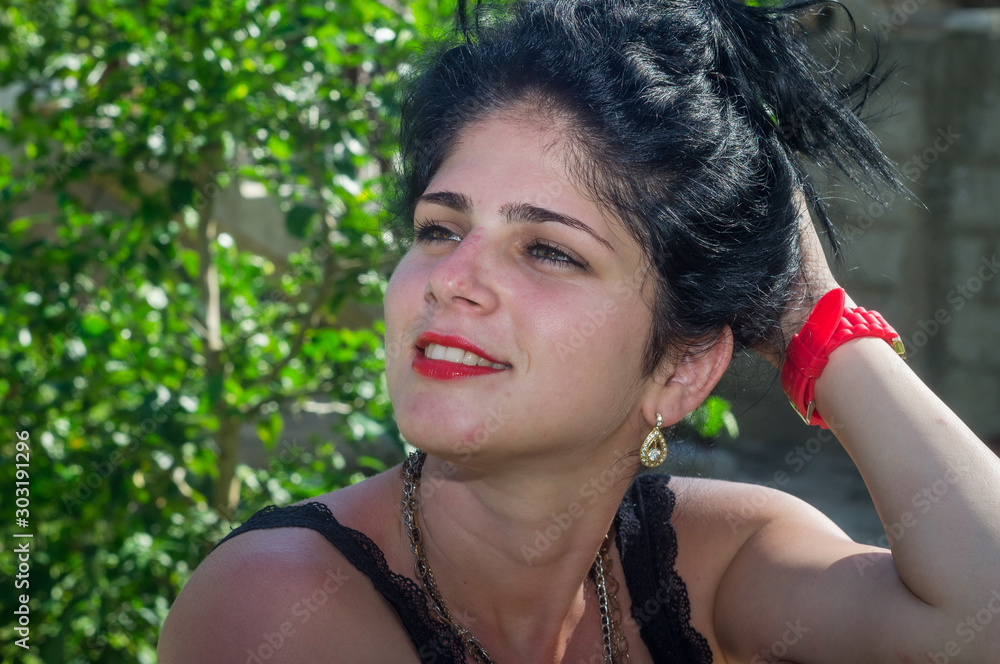 Cute Cuban girl holding a hand in her black hair, green eyes and red ...