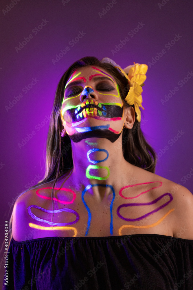 Retrato de joven maquillada de catrina con pintura neón iluminada con ...