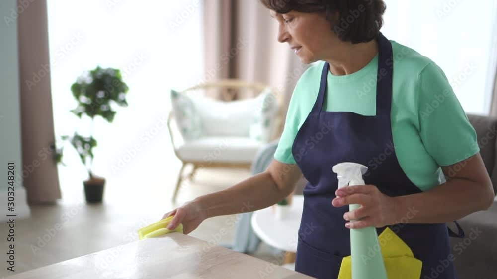 Old american housewife clean table standing in apartment interior ...