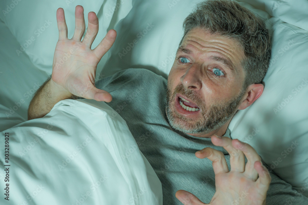 stressed and scared man alone in bed awake at night in fear after ...