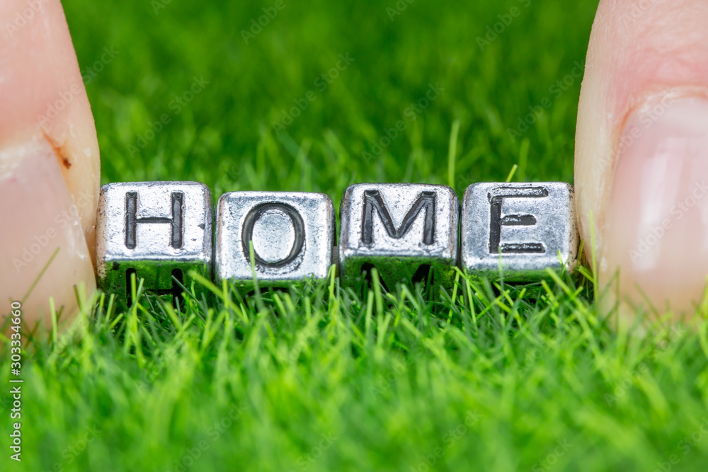Word HOME written in metal letters laid on grass and held between the ...