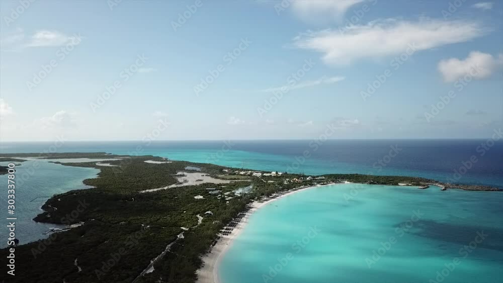 Slow flight over a moon shaped Bahamian island beach from high done by ...