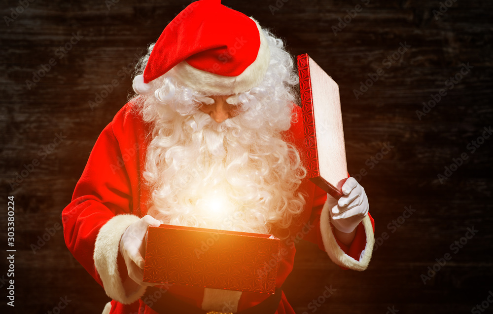 Santa Claus opening a gift box and being invested by a magical light ...