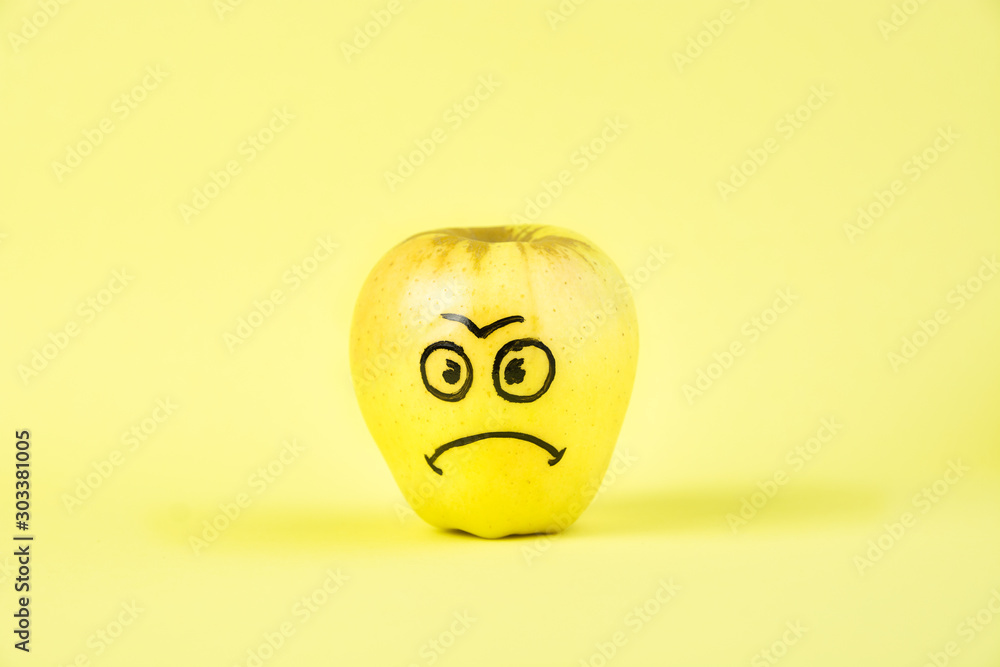 sad Face on an apple - abstract image of human emotions on a yellow ...