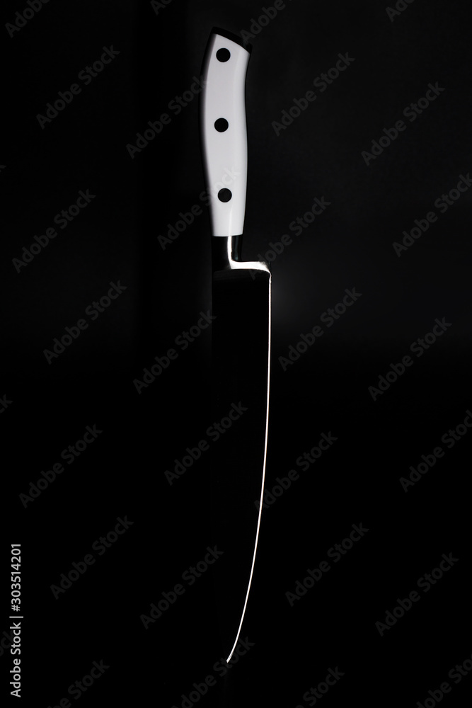 Kitchen knife with a white handle on a black background. A sharp blade ...