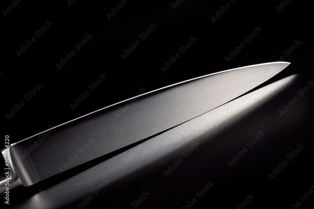 Kitchen knife with a white handle on a black background. A sharp blade ...