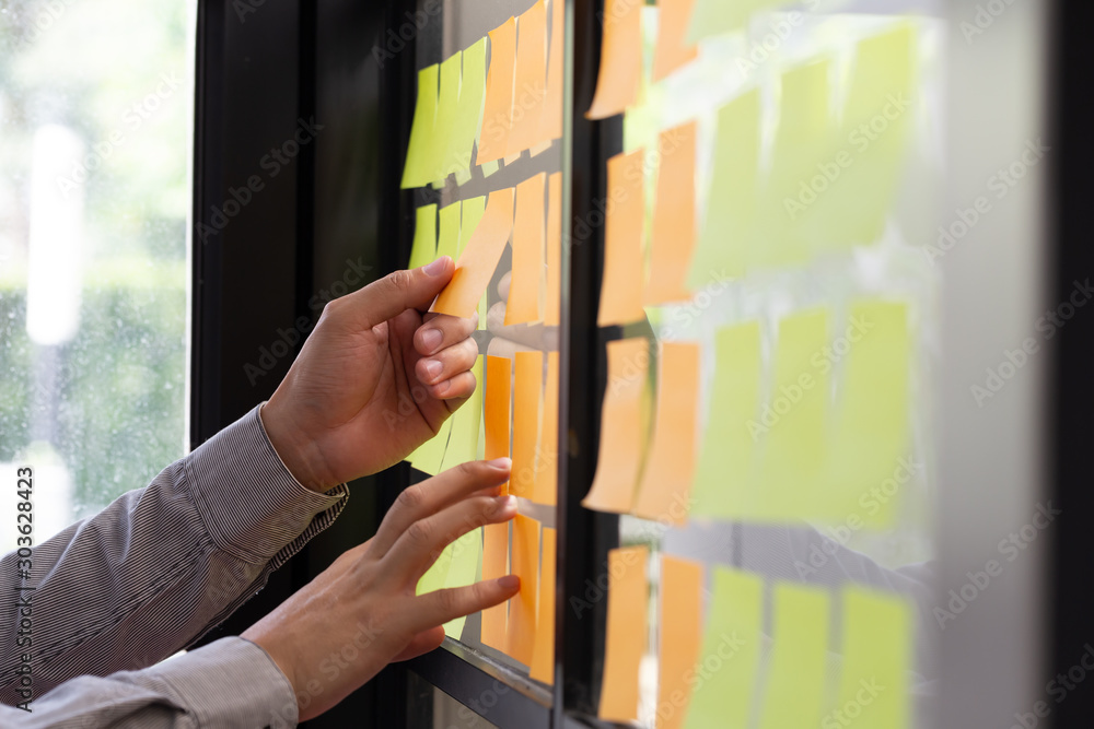 IT worker tracking his tasks on kanban board. Using task control of ...